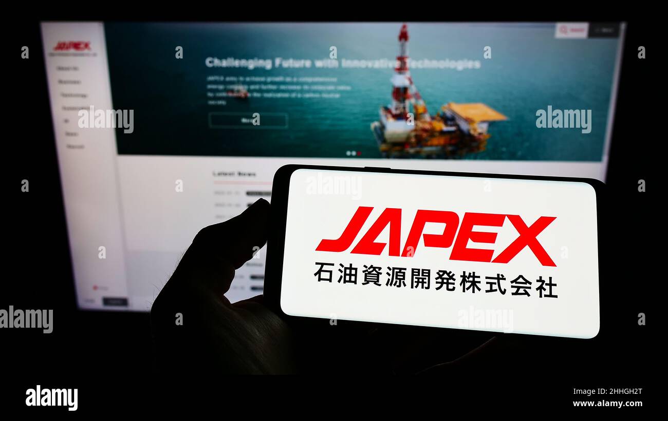 Person holding smartphone with logo of Japan Petroleum Exploration Company Limited (JAPEX) on ...