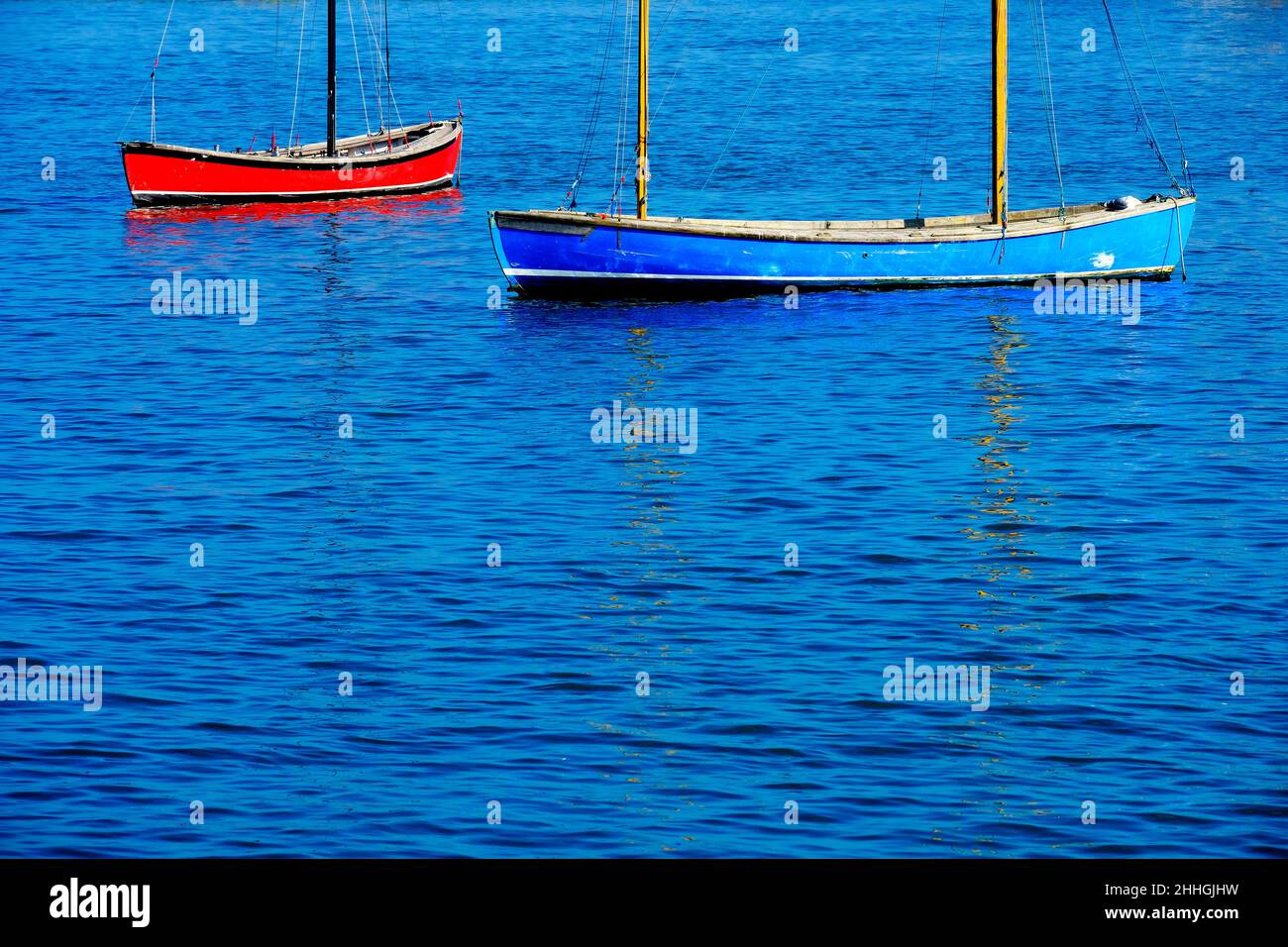 Red and blue sailboats floating in water at lake or ocean boats Stock ...