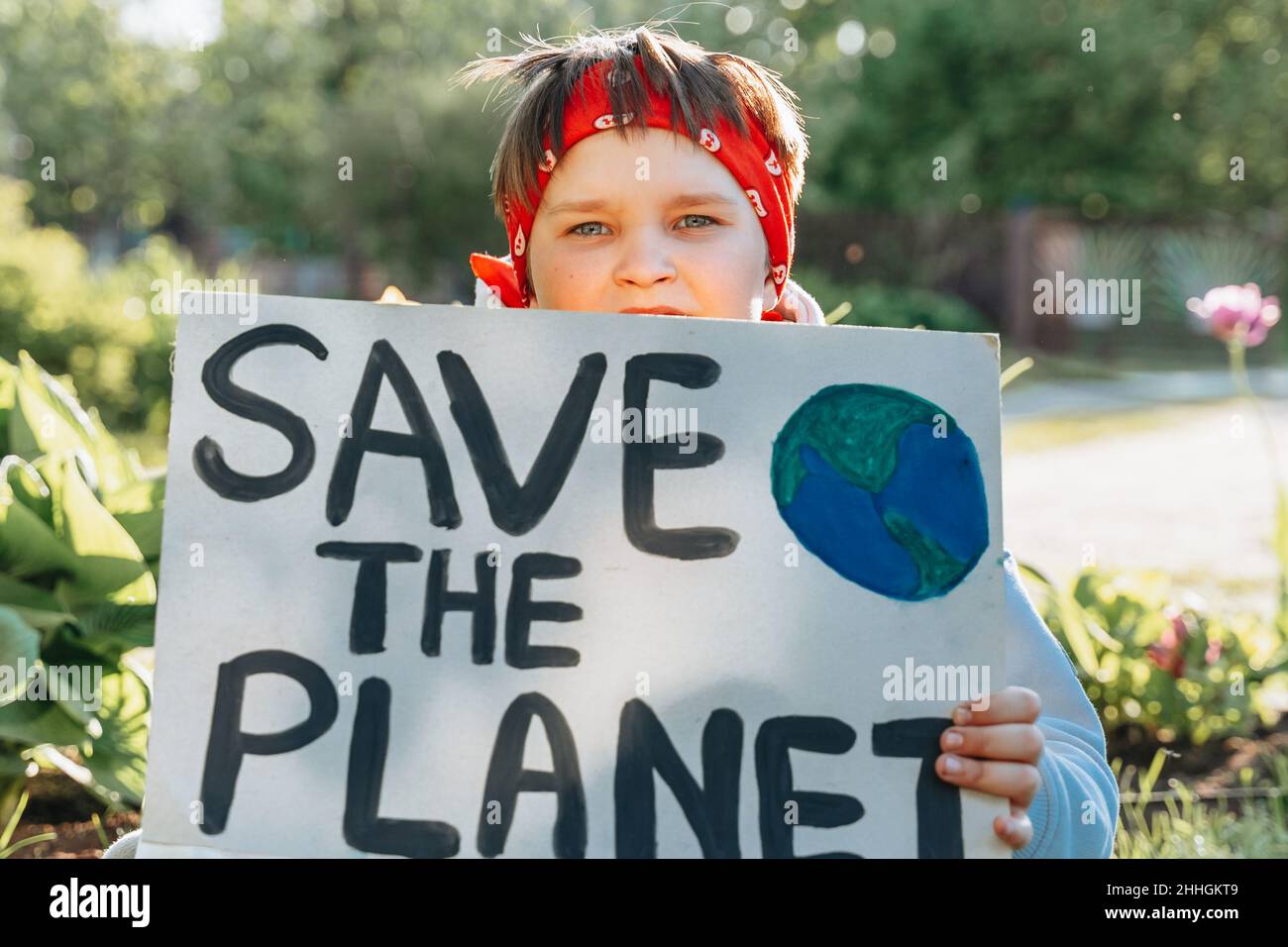 portrait of young boy standing with Save the planet Poster on school ...