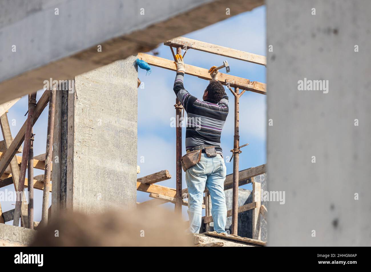 a male builder builds a building hammering a nail while standing on a ...