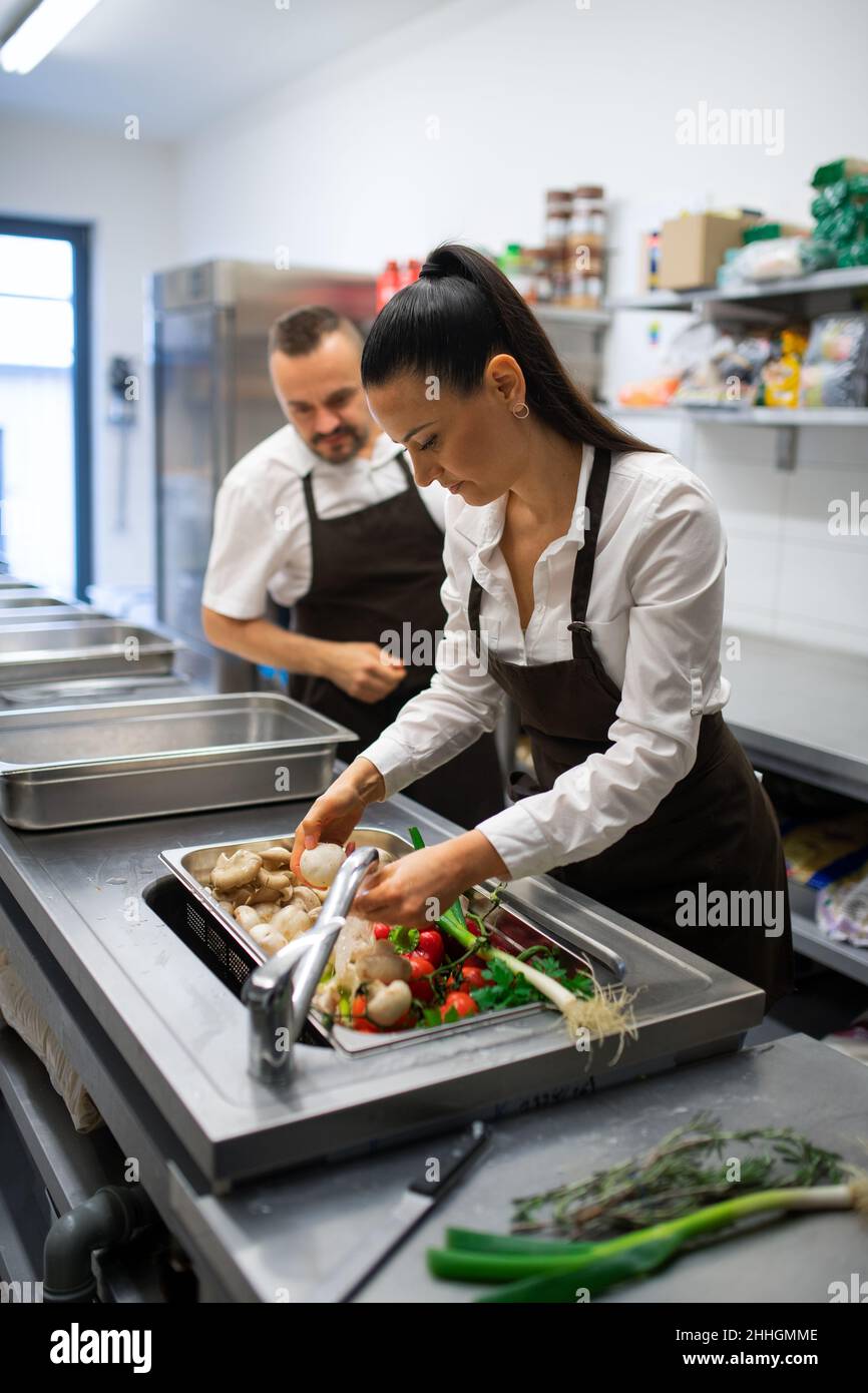 Cook washing vegetables in sink in commercial kitchen Stock Photo - Alamy