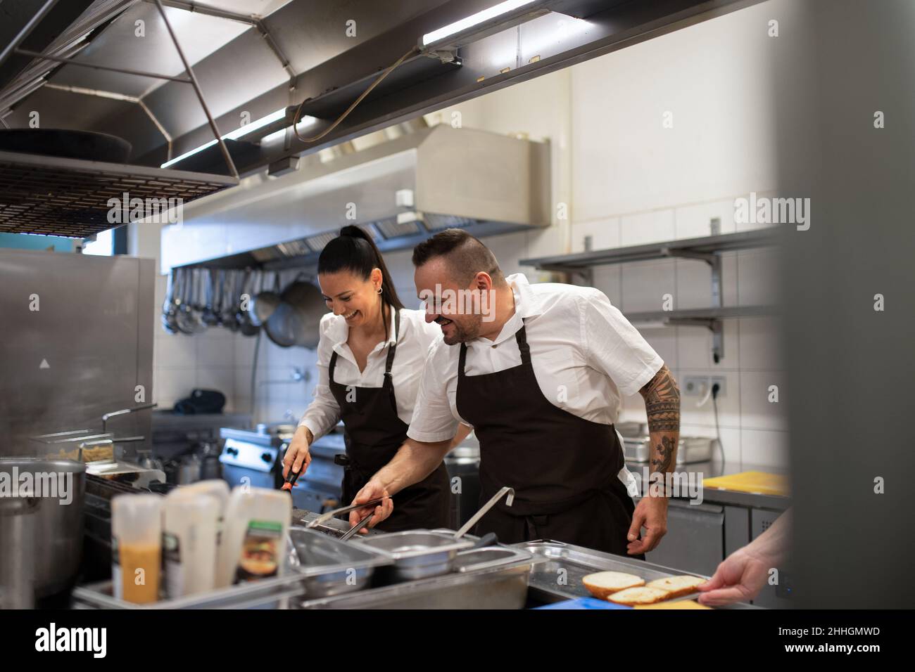 Happy chef and cook working on their dishes indoors in restaurant ...