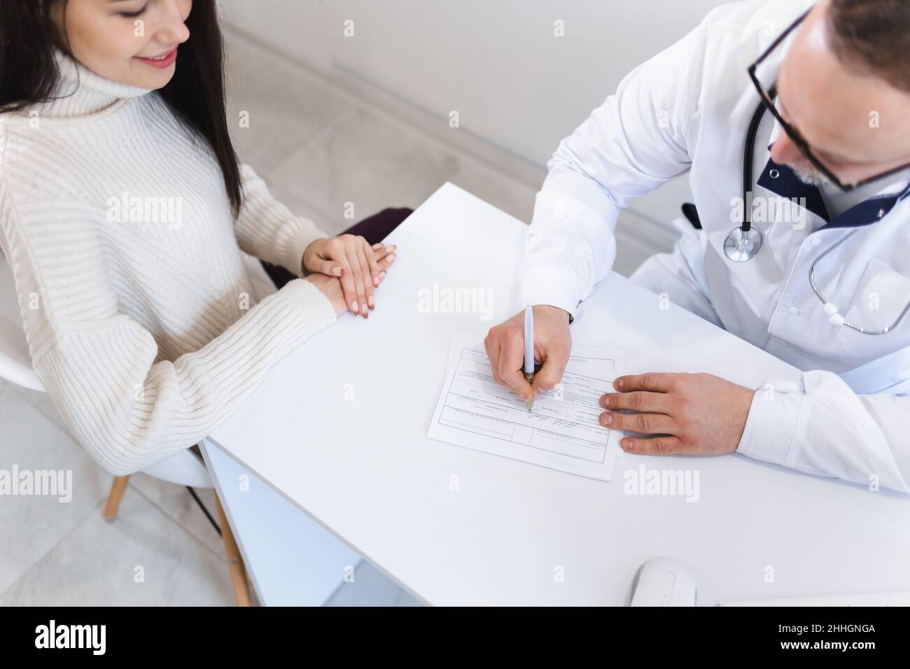 Top view of patient and doctor taking notes. The physician fills out ...