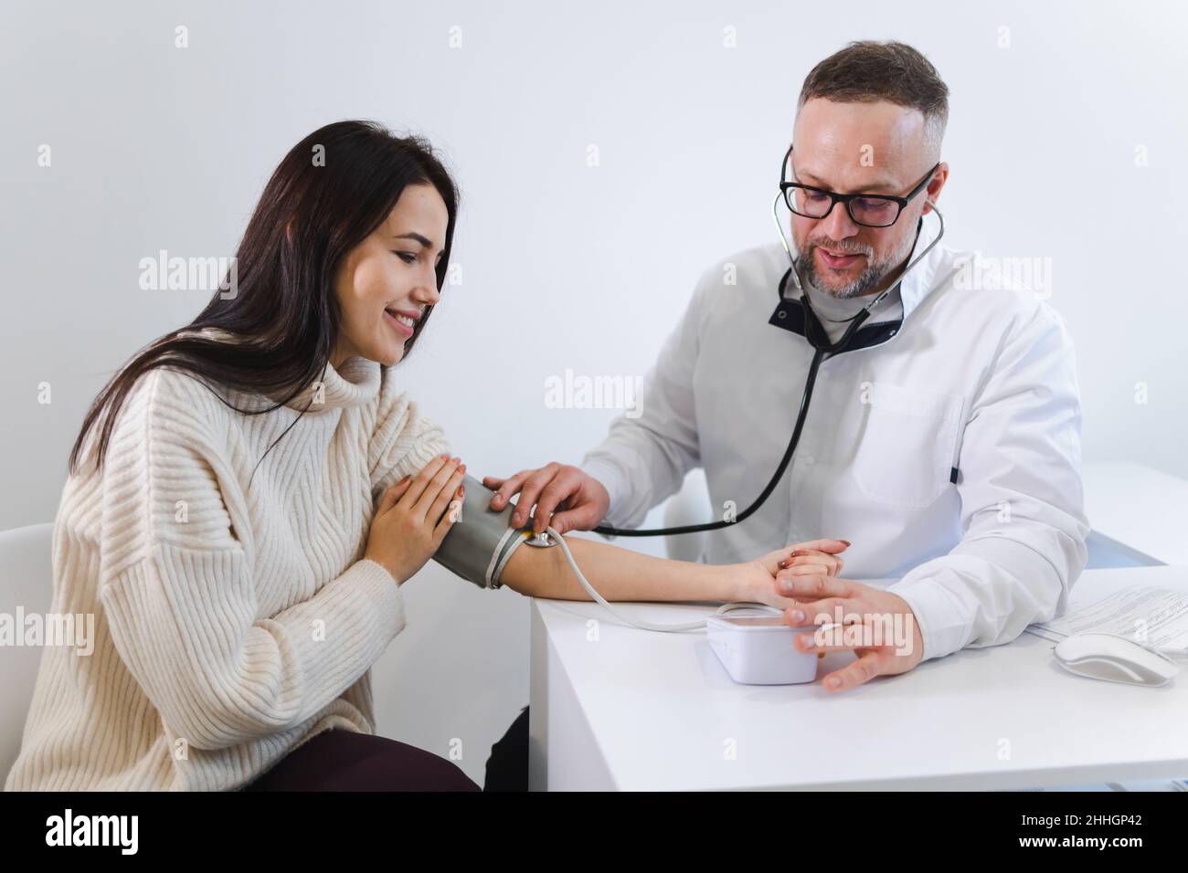 Male doctor at the medical examination measures the blood pressure of a ...