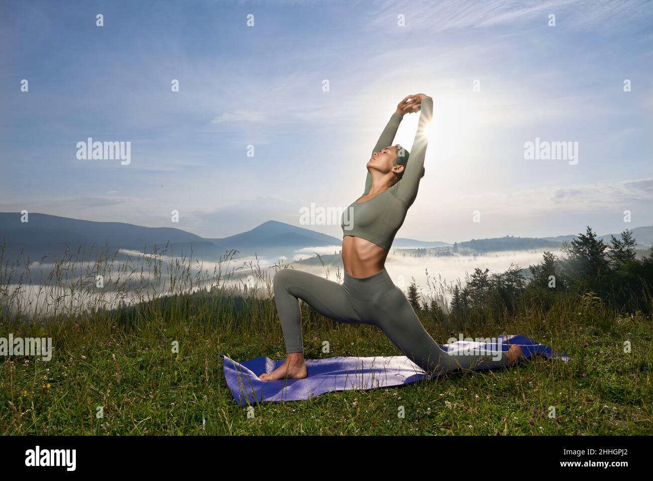 Healthy fit woman with slender body doing yoga exercise among green ...