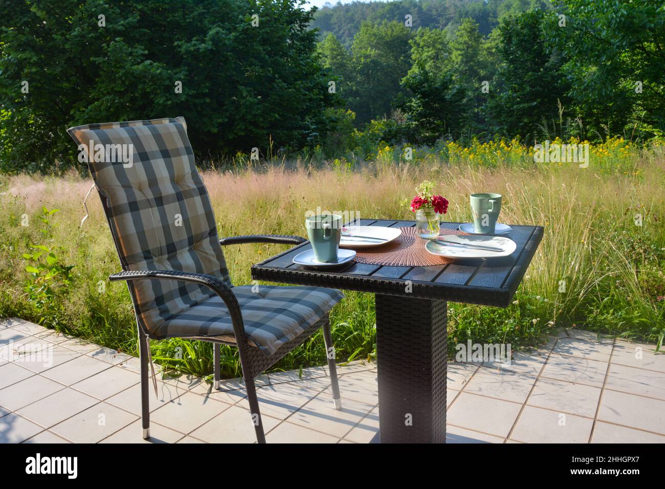 Breakfast on the terrace in front of green nature on a beautiful summer ...