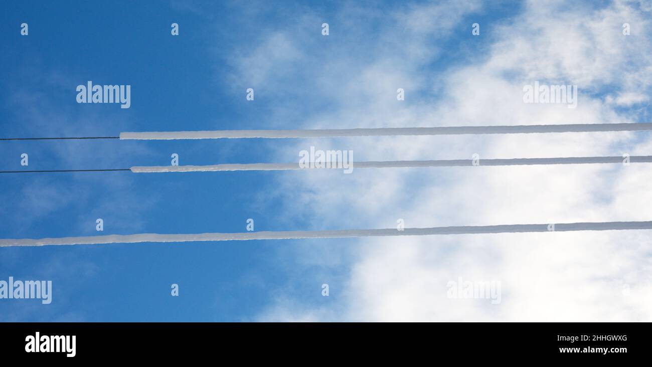 The electric cable is covered with frozen snow and frost after sleet ...