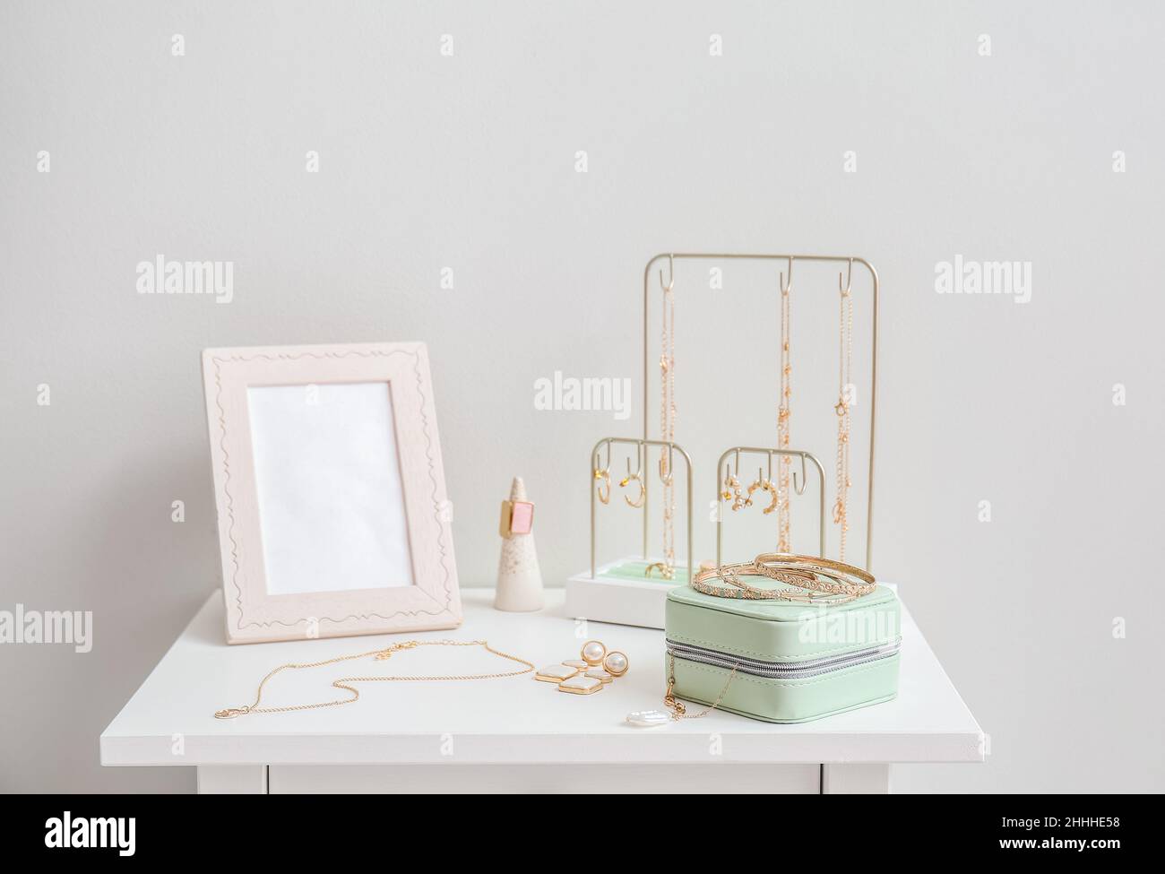 Table with stylish jewelry and photo frame near light wall Stock Photo ...