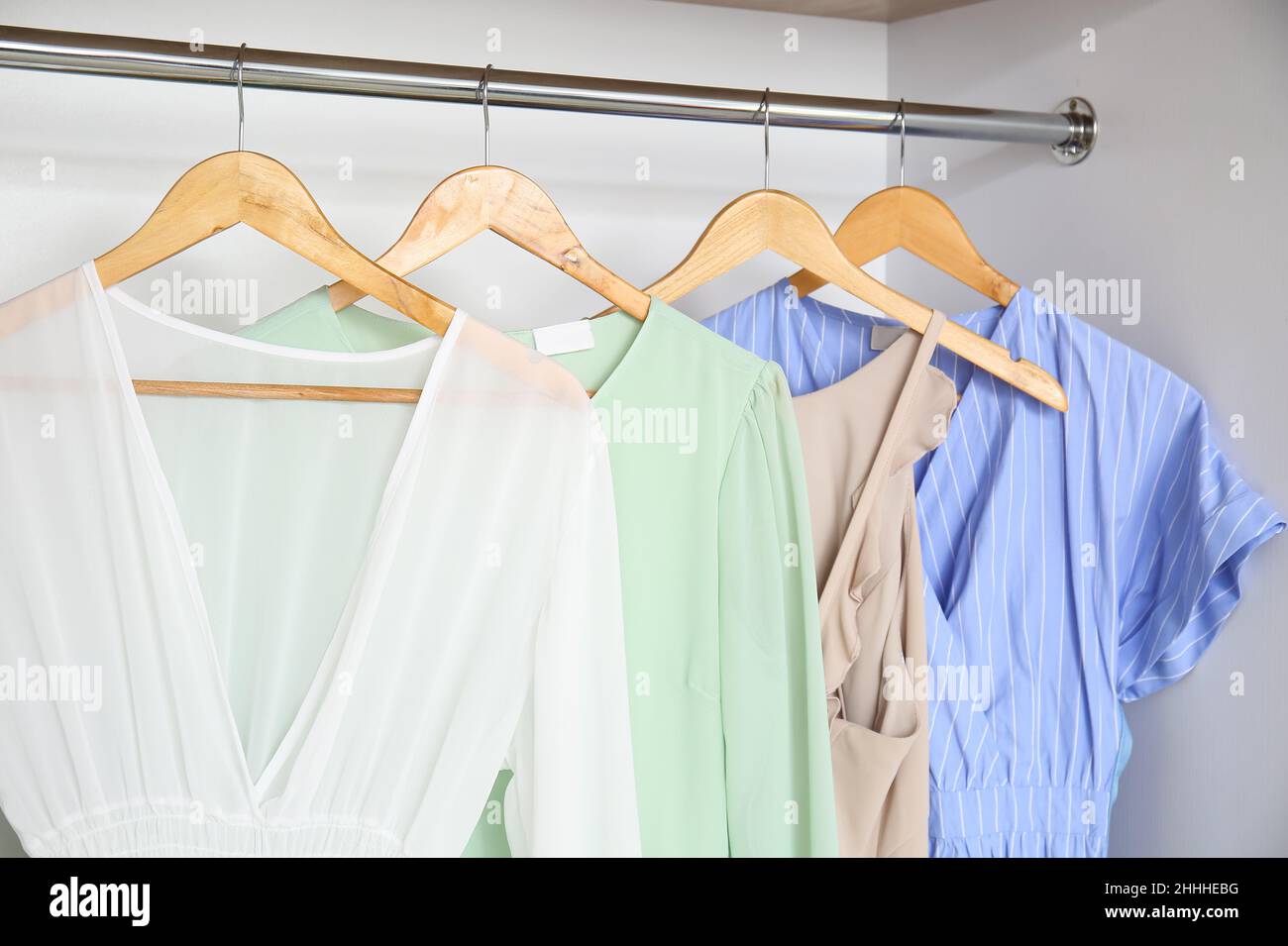 Stylish dresses hanging in wardrobe, closeup Stock Photo - Alamy