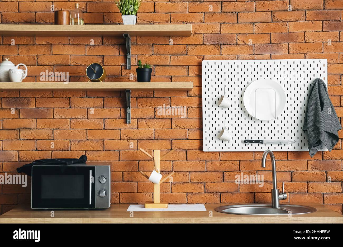 Peg board with kitchenware hanging on brick wall Stock Photo - Alamy