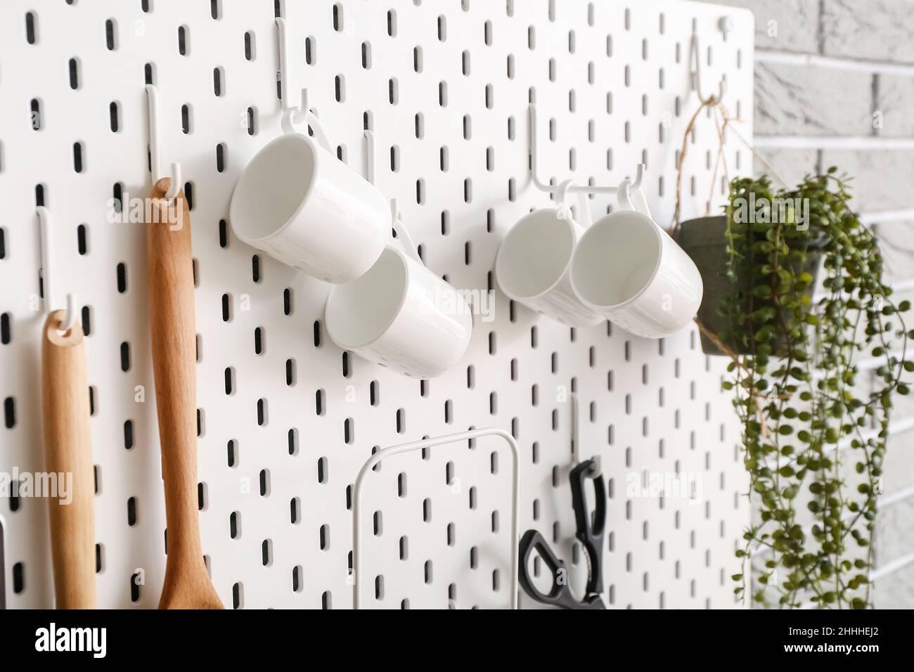 Pegboard with cups and kitchen utensils on wall Stock Photo - Alamy