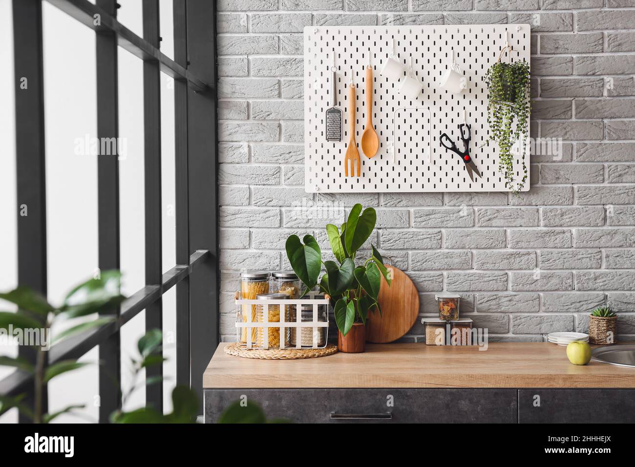 Stylish counter and pegboard on grey brick wall in modern kitchen Stock ...