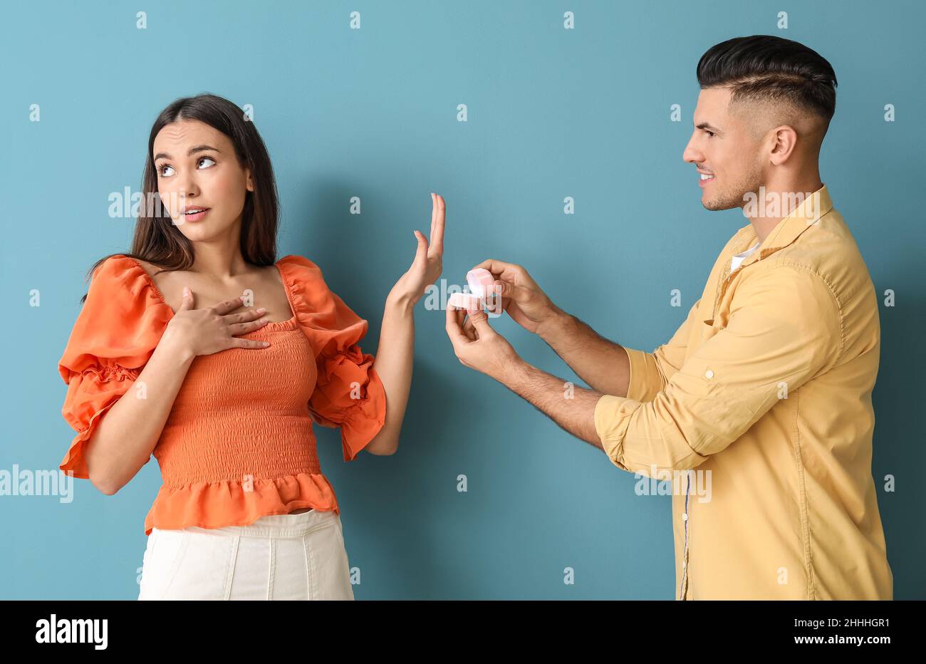 Young woman rejecting marriage proposal on blue background Stock Photo ...