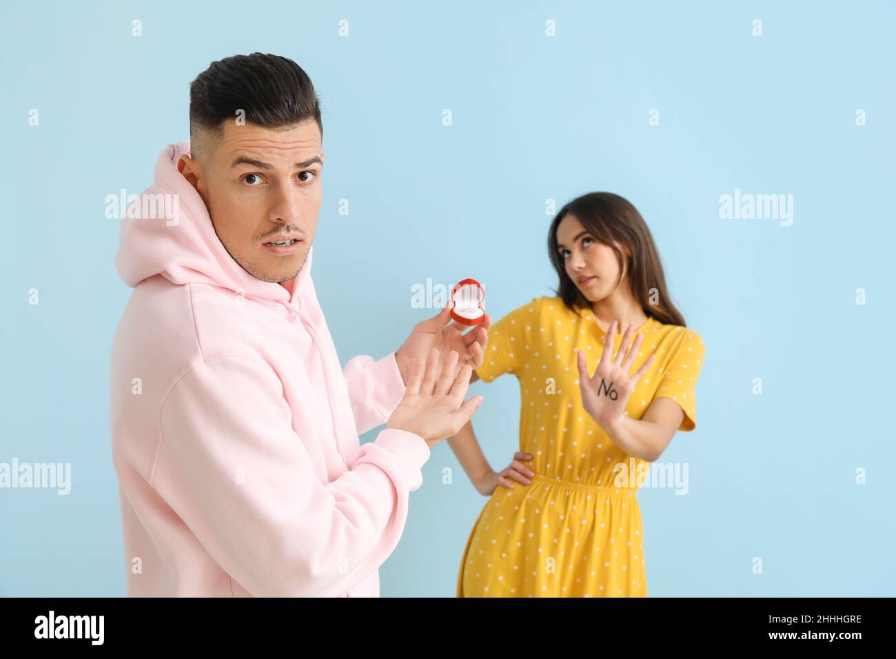 Young woman rejecting marriage proposal on blue background Stock Photo ...