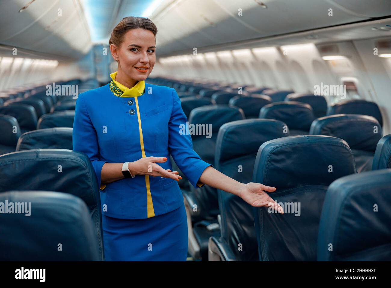 Female flight attendant pointing at passenger seat in airplane cabin ...