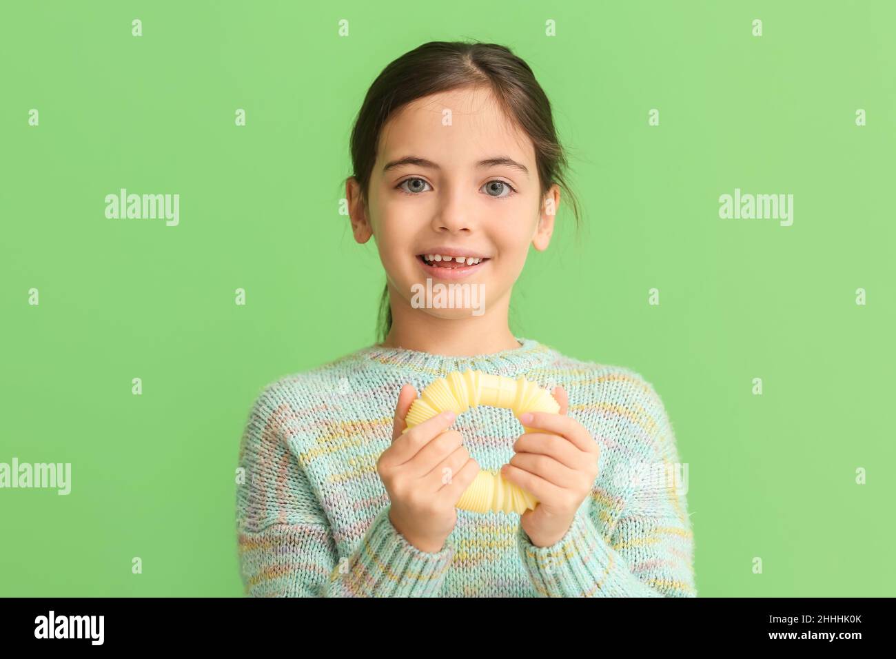 Little girl with yellow Pop Tube on green background Stock Photo - Alamy
