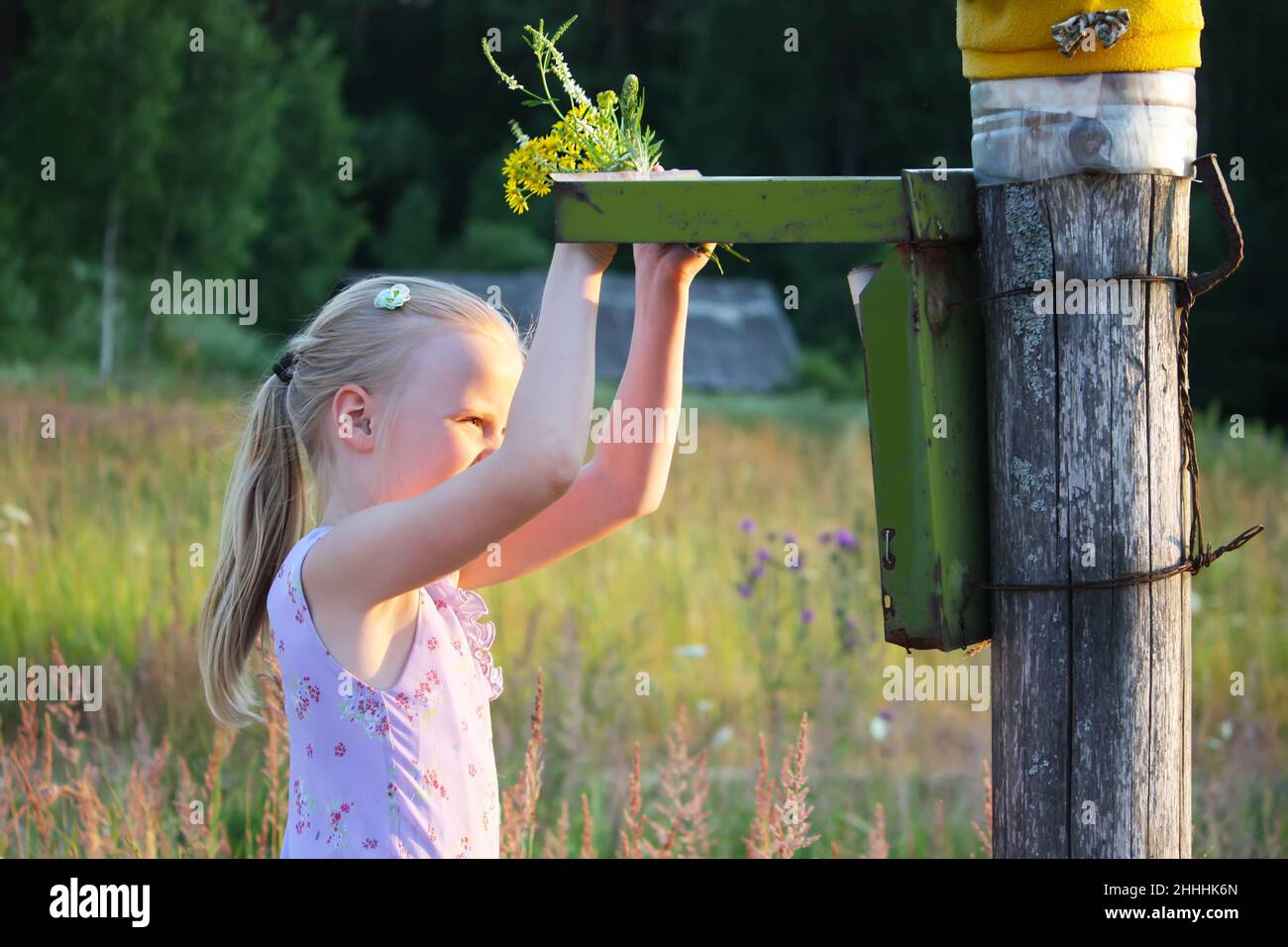 Adorable little blonde girl opening metal mailbox in the countryside ...
