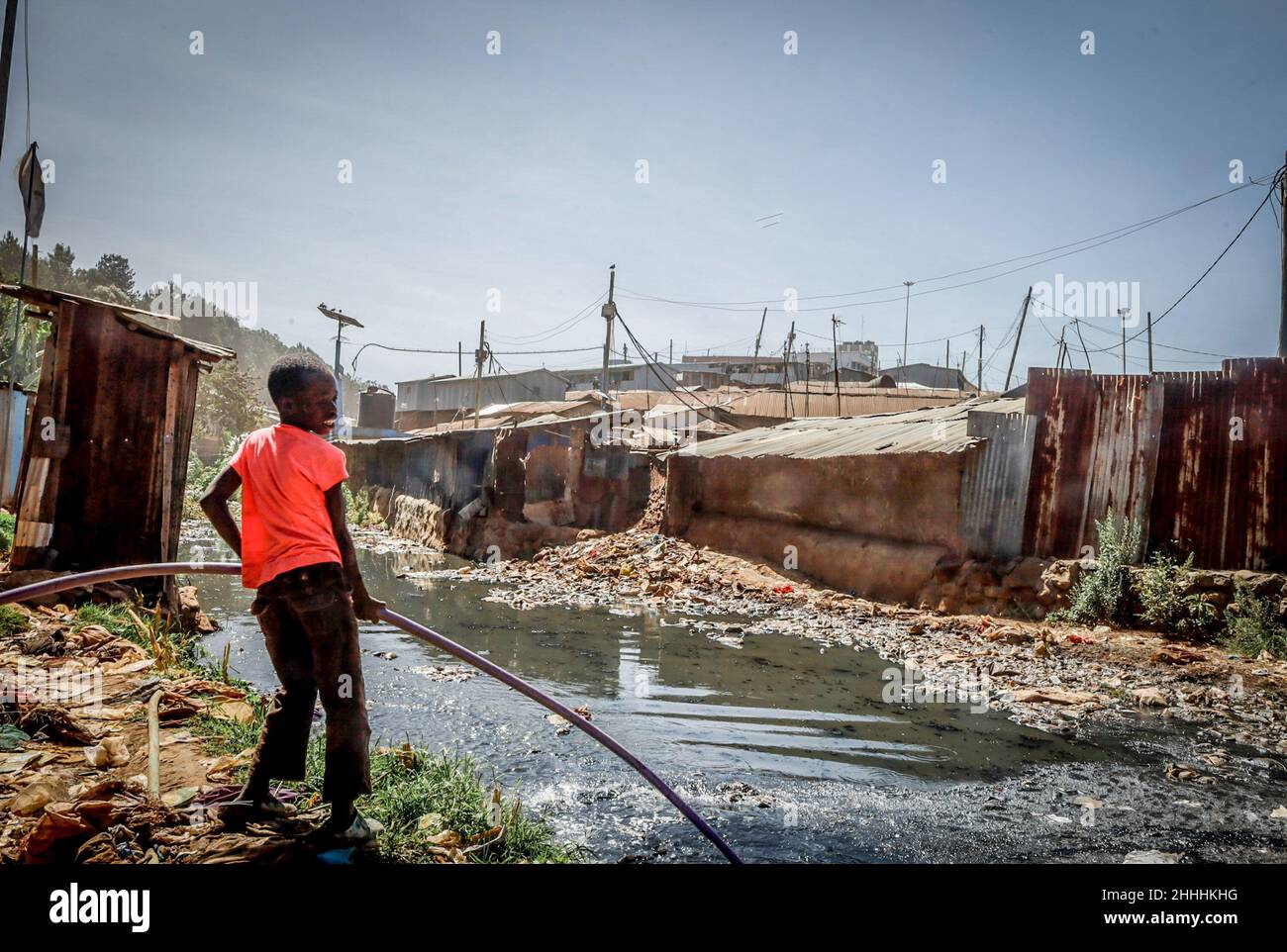 A young boy plays by a local sewer river and a dumping site in Kibera ...