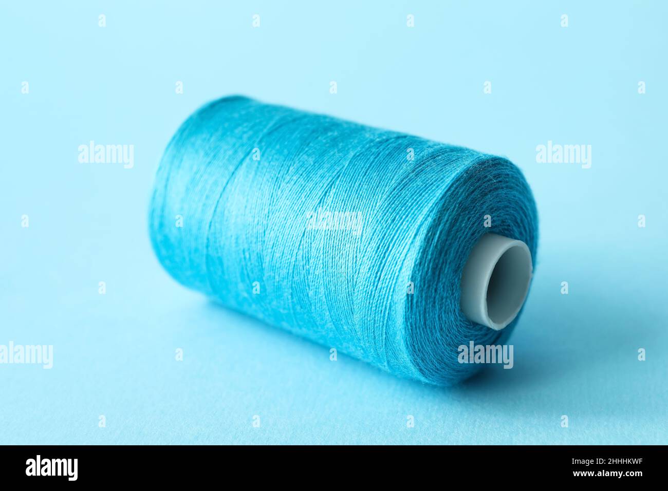 Blue sewing thread spool on color background Stock Photo - Alamy