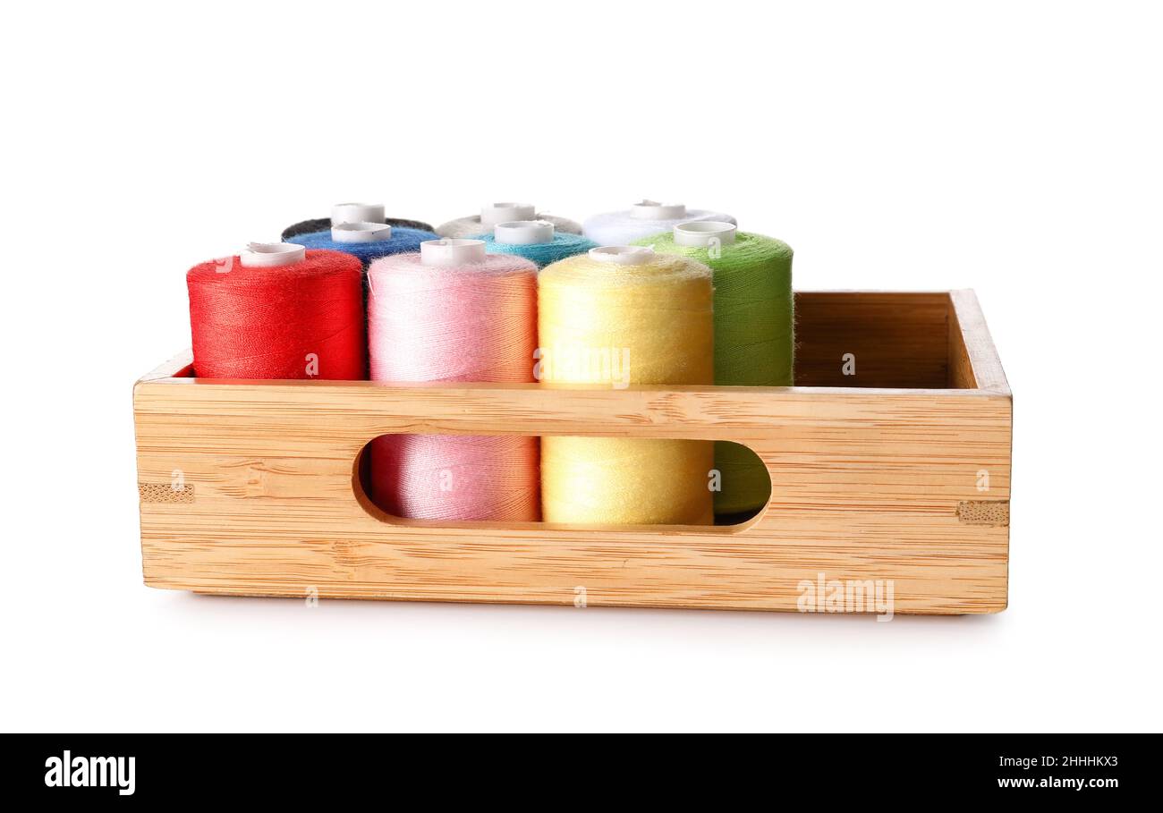 Wooden box with different sewing thread spools on white background ...