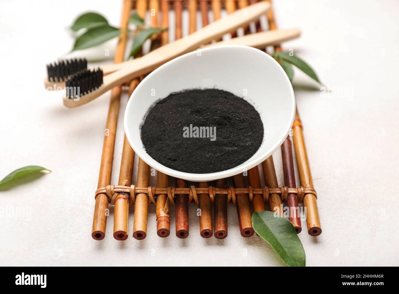 Bowl with activated charcoal tooth powder and toothbrushes on white ...