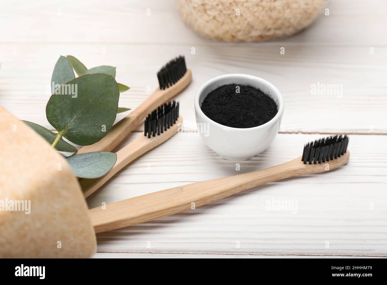 Bowl with activated charcoal tooth powder and brushes on white wooden ...
