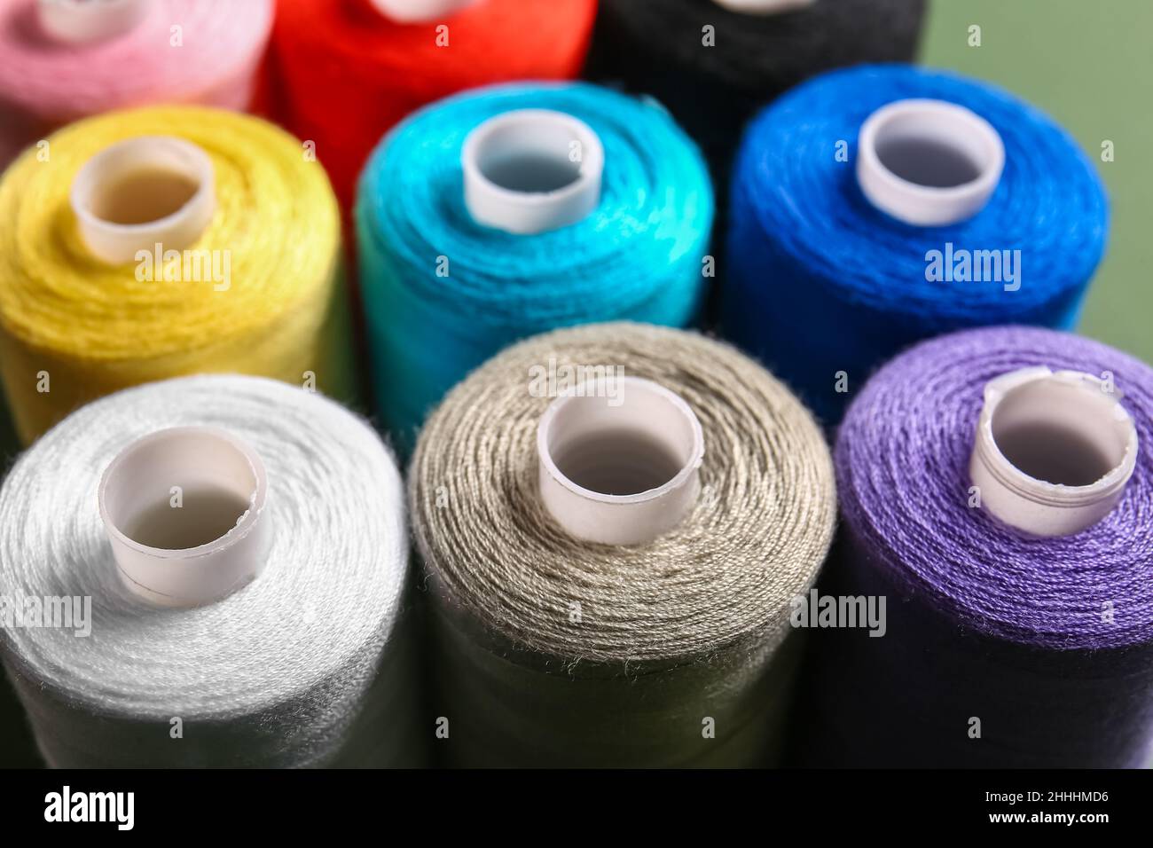Closeup view of colorful sewing threads on green background Stock Photo ...