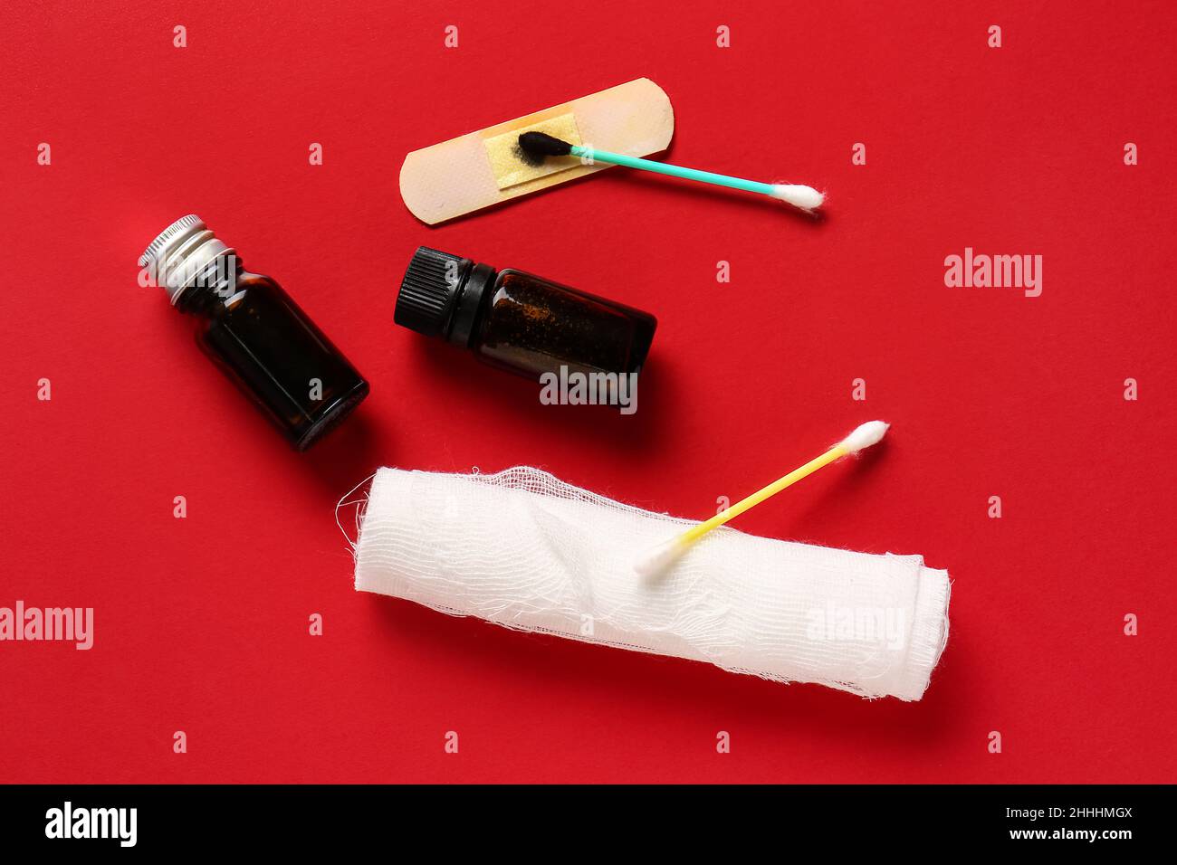 Bottles with iodine, medical plaster, cotton swab and gauze roll on red ...