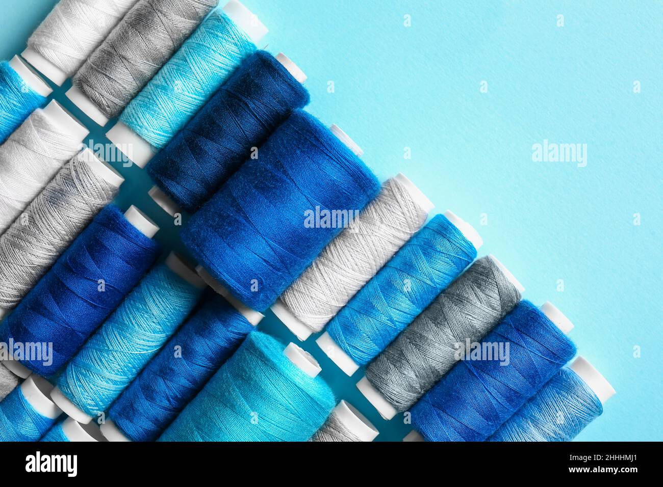 Spools with grey and blue sewing threads on color background Stock ...