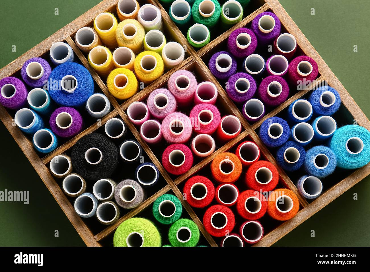 Wooden boxes with sewing threads on green background, closeup Stock ...