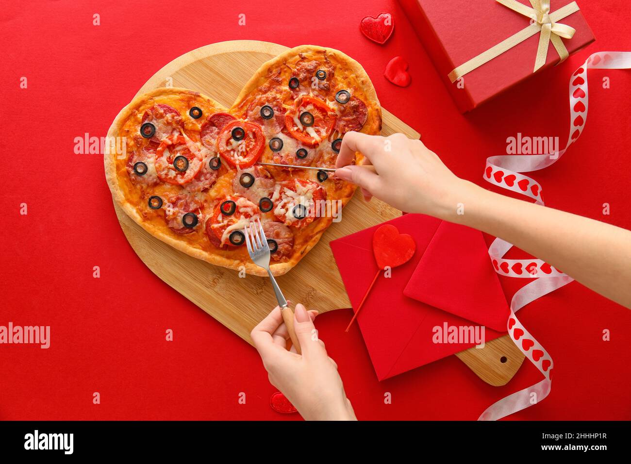 Woman eating tasty heart-shaped pizza on red background. Valentine's ...