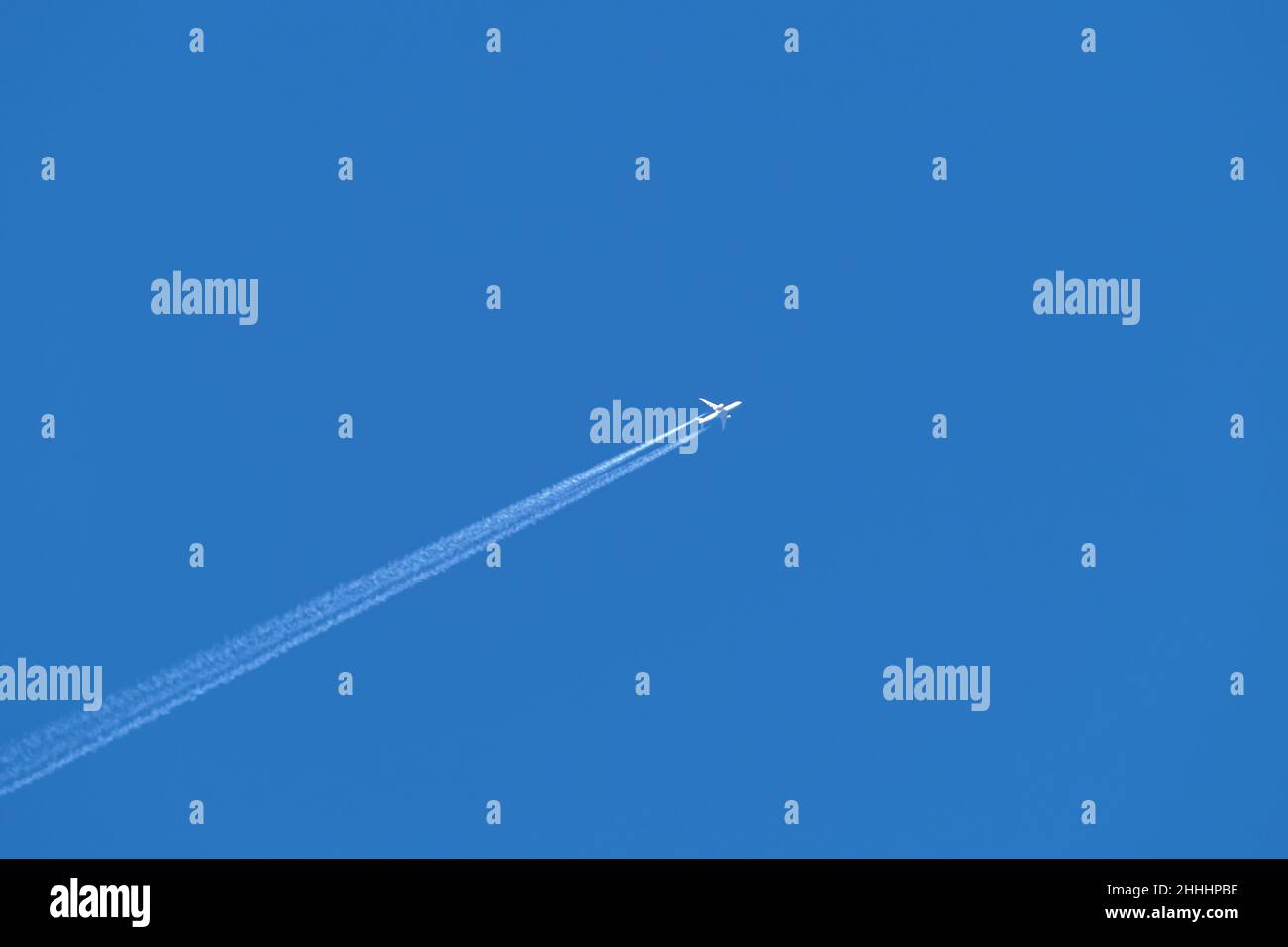 Distant passenger jet plane flying on high altitude on clear blue sky ...