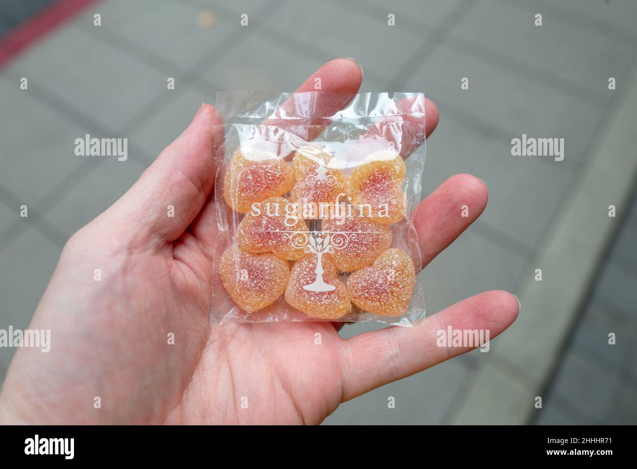 Close-up of human hand holding package of Sugarfina candies with logo ...