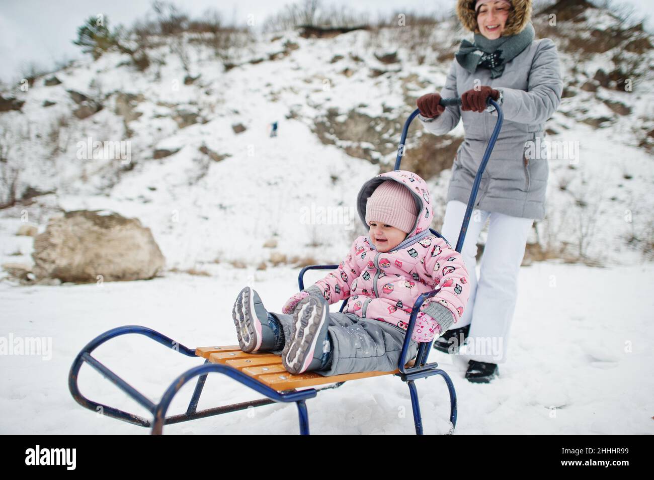 Mother and baby girl enjoy a sleigh ride. Child sledding. Kid riding a ...