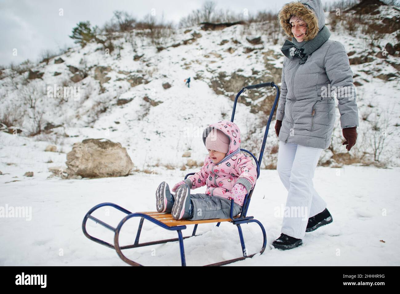 Mother and baby girl enjoy a sleigh ride. Child sledding. Kid riding a ...