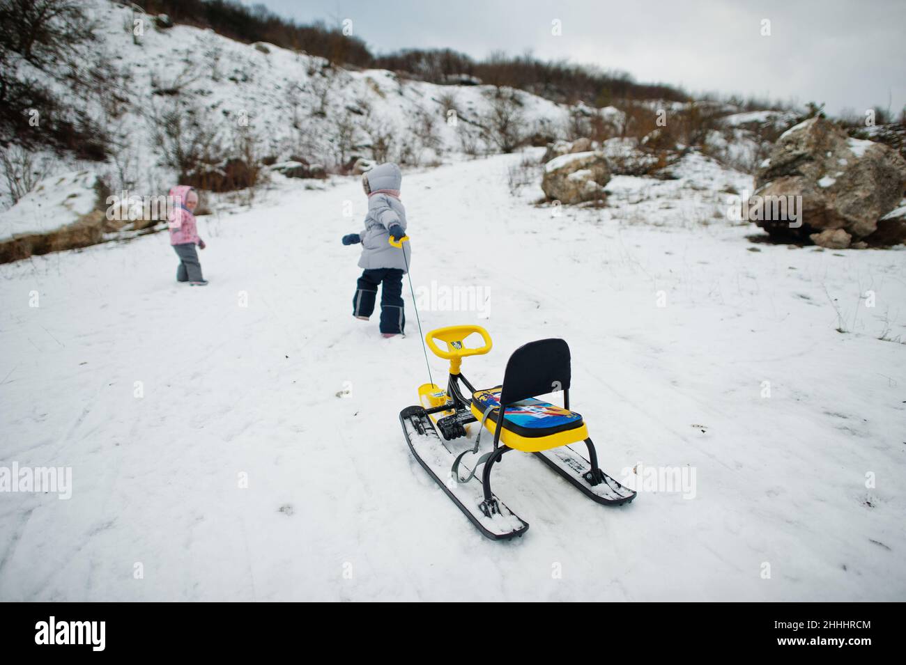 Two baby girl enjoy a sleigh ride. Child sledding. Kid riding a sledge ...