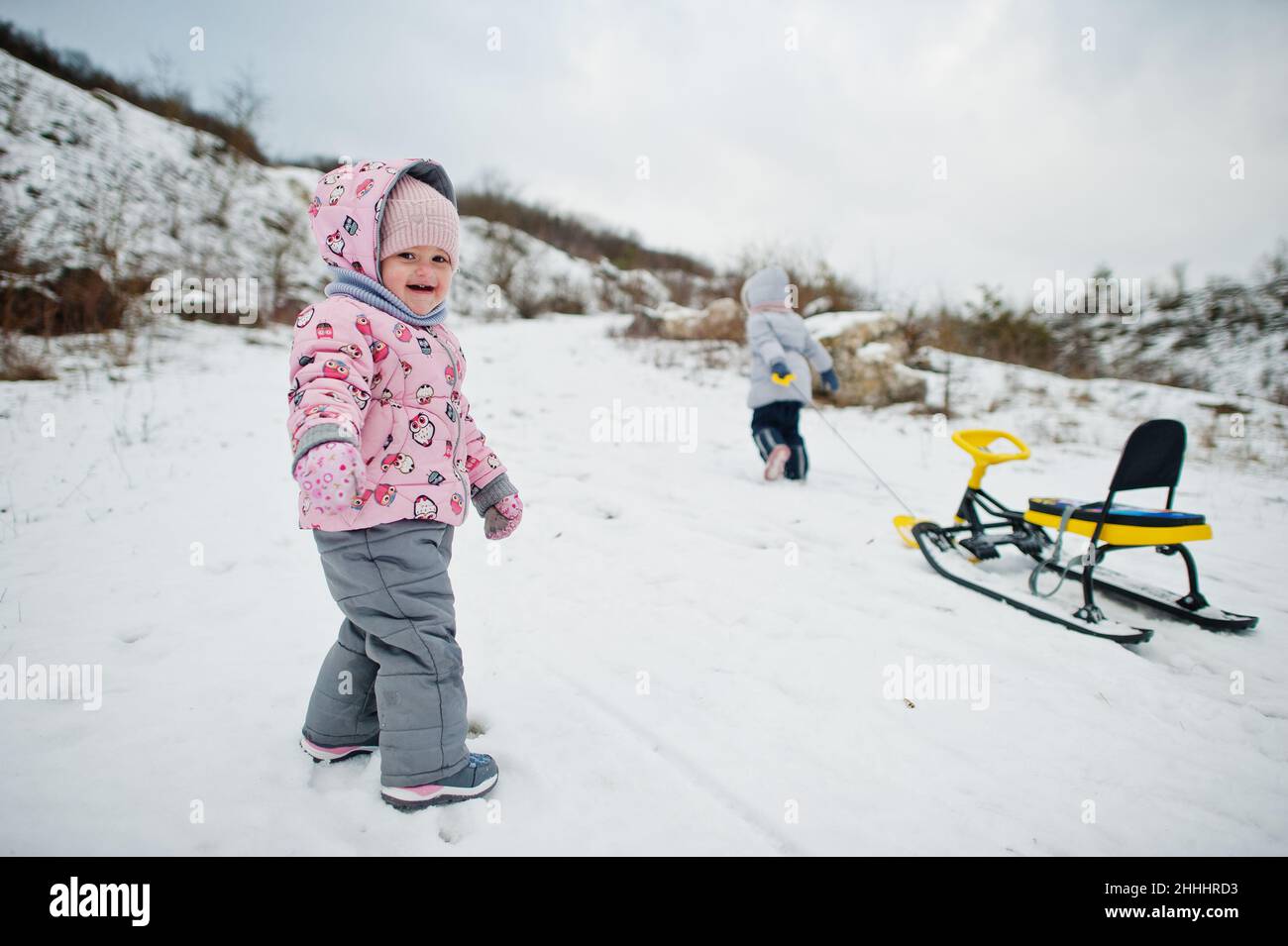 Two baby girl enjoy a sleigh ride. Child sledding. Kid riding a sledge ...