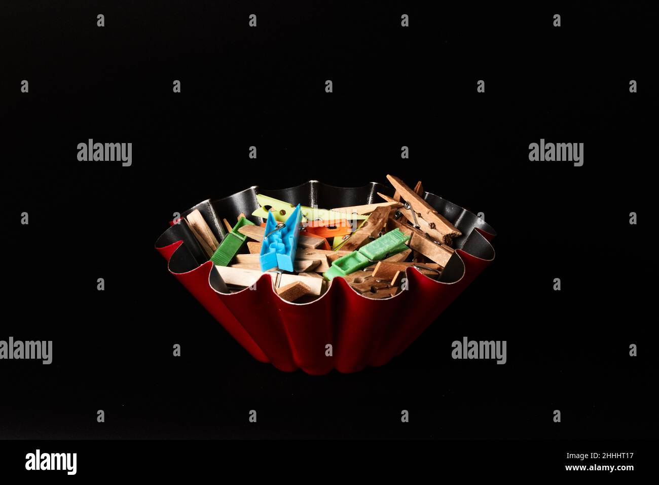 Red flan box on a black background filled with clothespins, some made ...