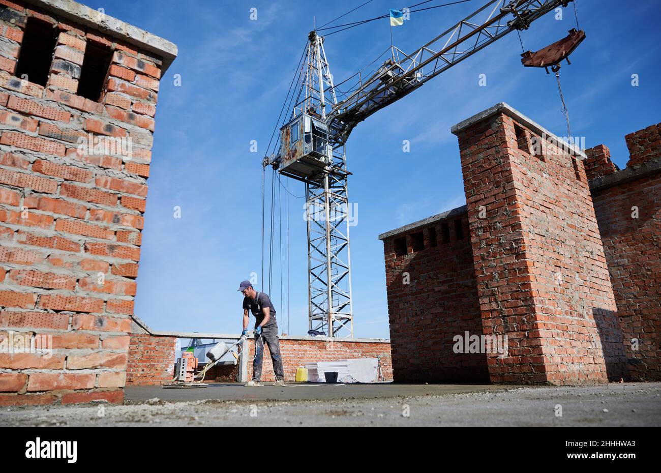 Man laborer using power trowel machine while screeding floor in ...
