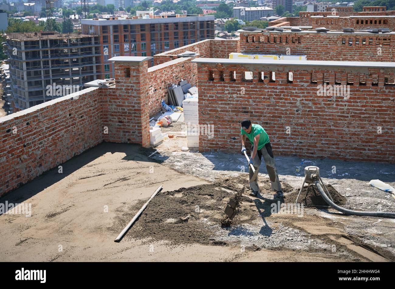 Male worker shoveling cementitious material or floor screed mix while ...
