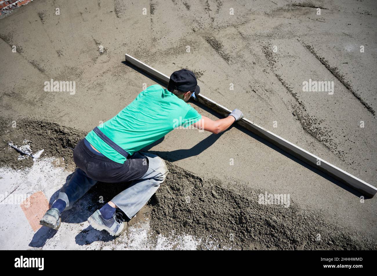 Top view of male worker placing screed rail on the floor covered with ...