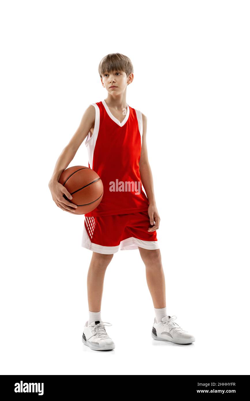 Studio portrait of young boy, basketball player in red uniform posing ...
