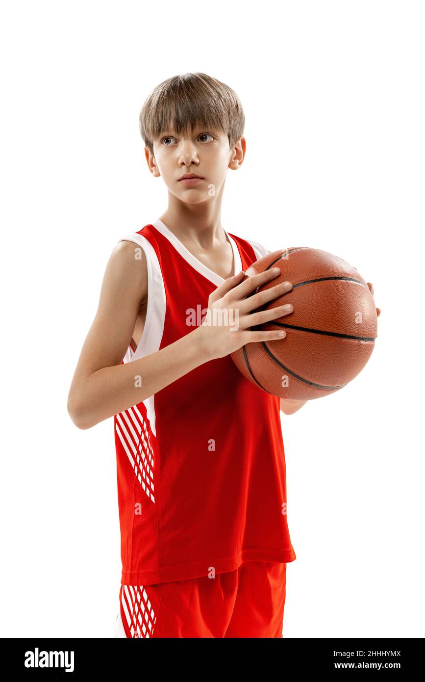 Studio portrait of young boy, basketball player in red uniform posing ...