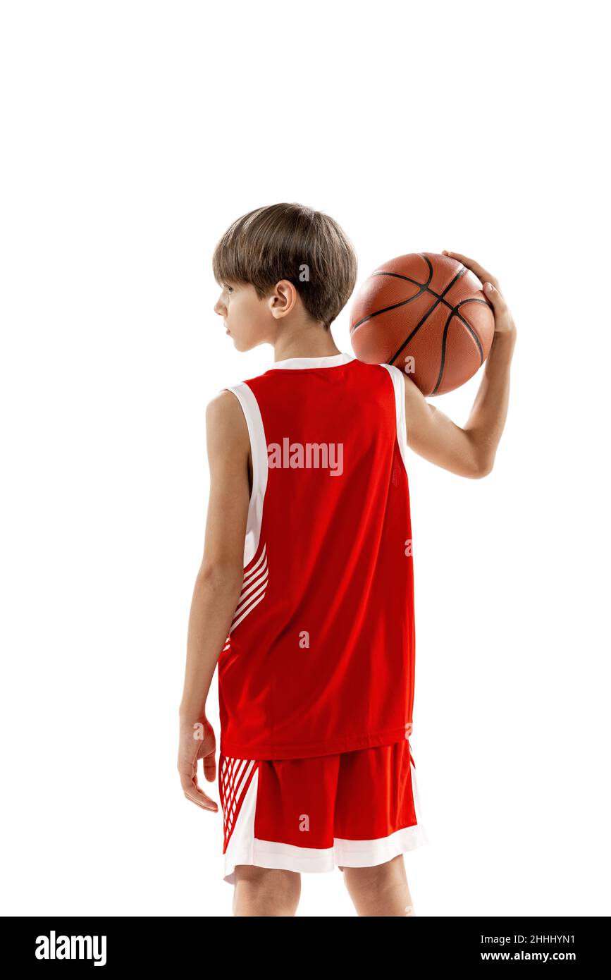 Studio portrait of young boy, basketball player in red uniform posing ...