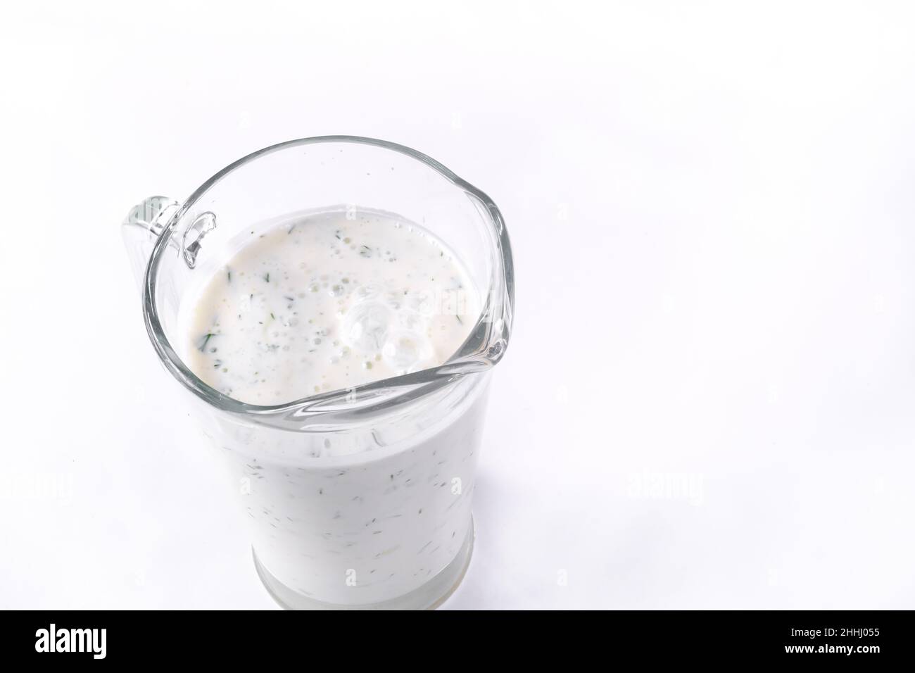 A glass of ayran with dill and parsley, highlighted on a white isolated ...