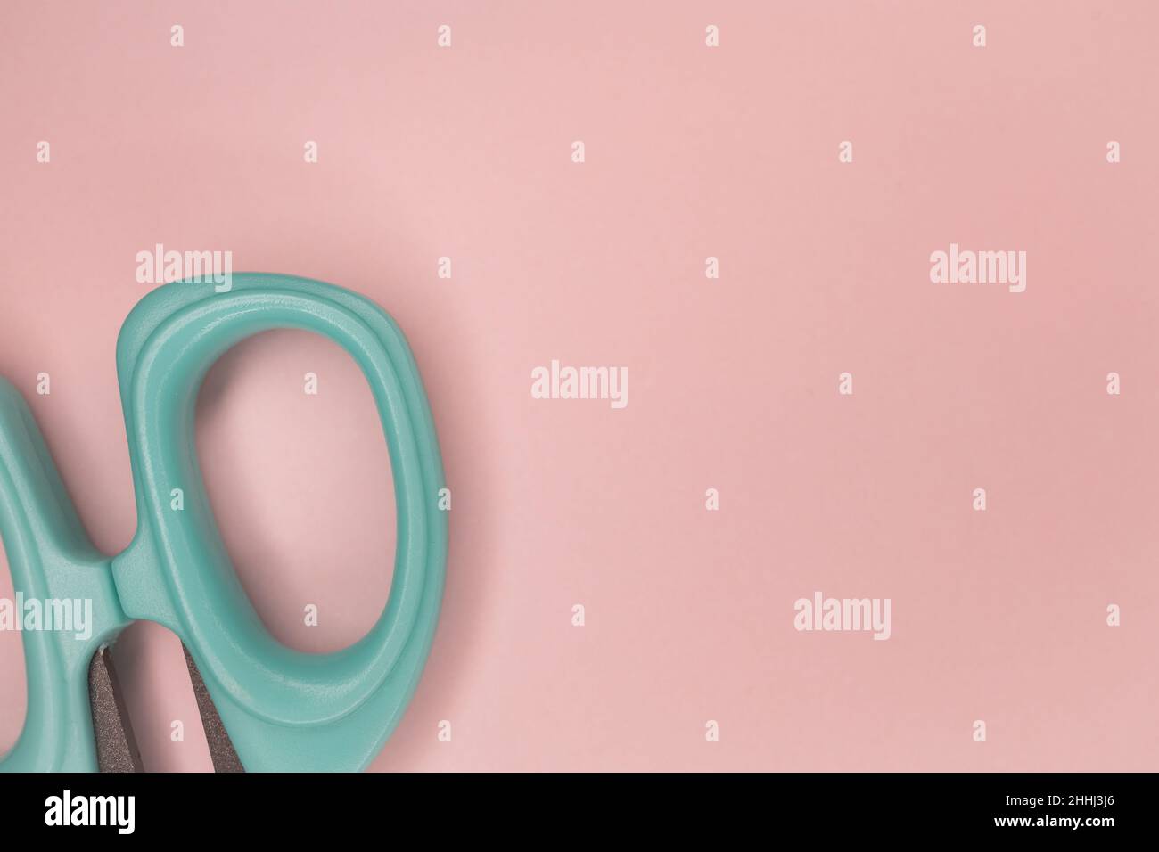 Teal scissors on light pink background Stock Photo - Alamy