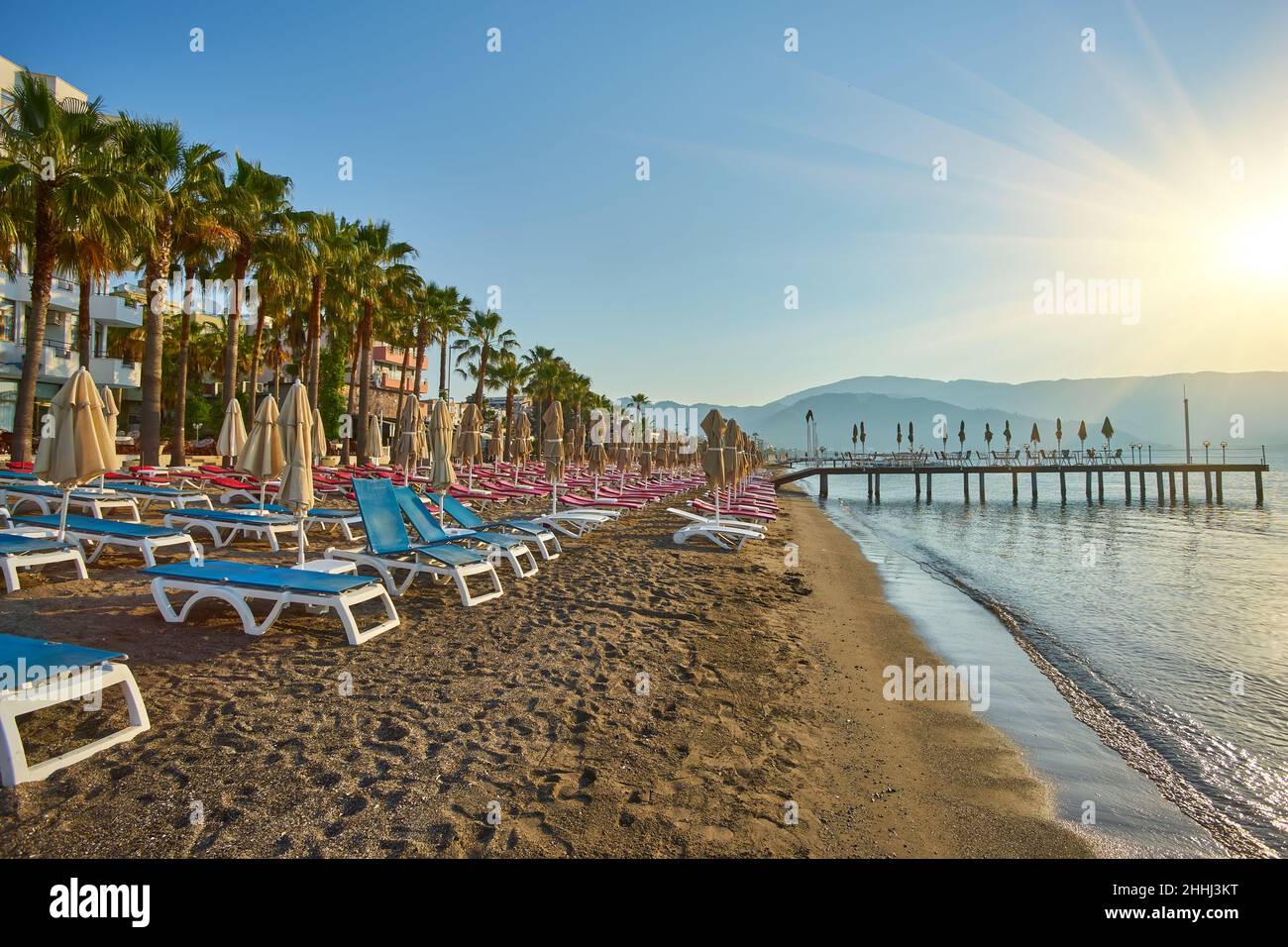 sandy beach without people and with sun loungers, umbrellas, palm trees ...