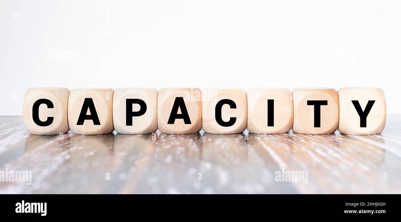 The word CAPACITY is written on a wooden blocks on a yellow background ...
