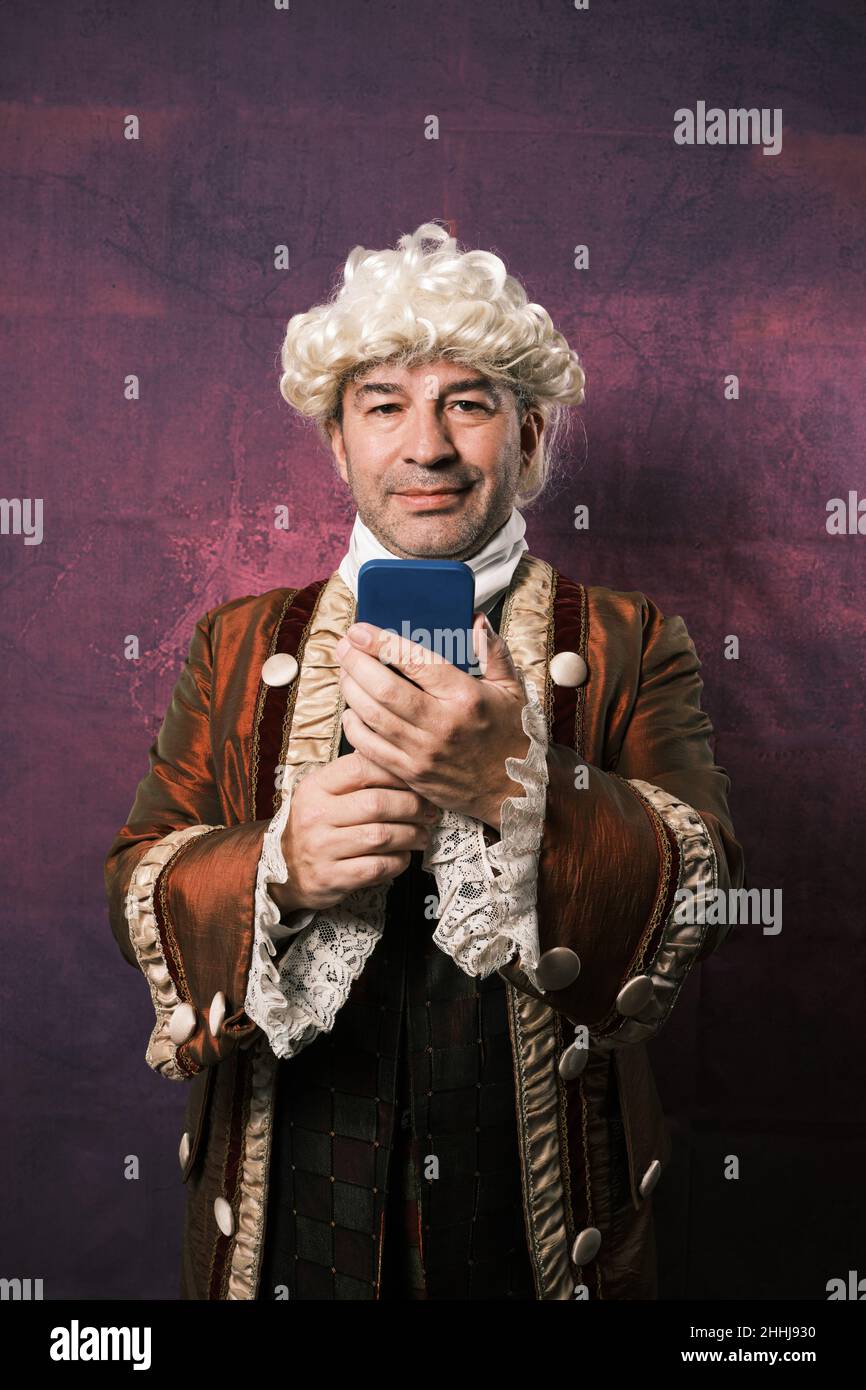 Adult man in classical medieval clothing using a mobile phone while ...