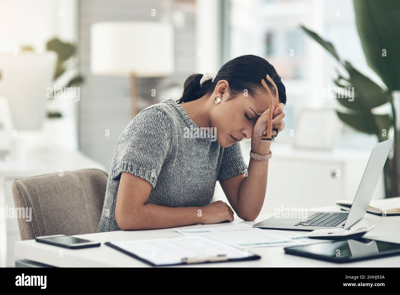 Sitting with a heavy workload and a sharp migraine Stock Photo - Alamy